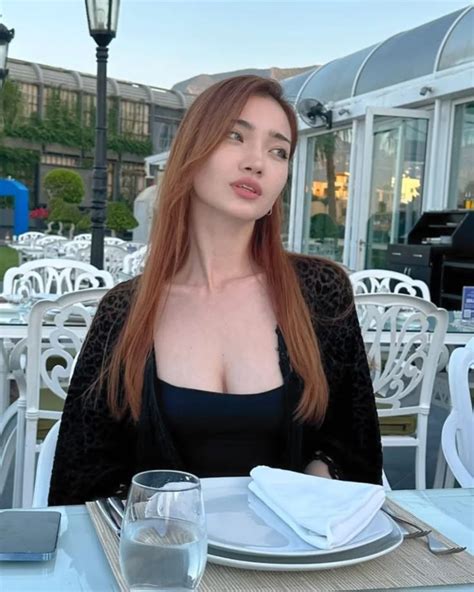 A Woman Sitting At An Outdoor Table With A Glass Of Water In Front Of Her