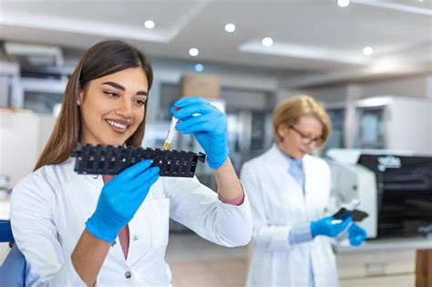 여성 연구 과학자는 분석기 의료 기계에 그들을 퍼 팅 하기 전에 혈액 샘플과 테스트 튜브를 보유 하 고 있습니다 과학자는 제약