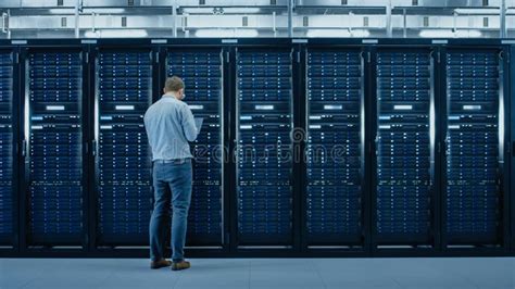 Data Center Engineer In High Visibility Vest Using Laptop Computer Server Farm Cloud Computing