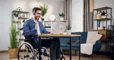 안경을 쓰고 헤드셋을 쓴 수염을 기른 남자가 현대 노트북에서 화상 회의를 하는 동안 말하고 몸짓을 하고 있다 집에서 일할 기회가 있는 장애가 있는 프리랜서 사진