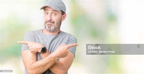 잘생긴 중 년 노인의 수석 남자 이상 스포츠 모자를 쓰고 절연 배경 손가락으로 양쪽 모두를 가리키는 다른 방향 반대 가리키기에 대한 스톡 사진 및 기타 이미지 Istock