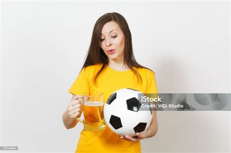 아름 다운 유럽 젊은 명랑 한 여자 축구 팬 또는 파인트 맥주의 얼굴 흰색 배경에 고립 된 축구공을 들고 노란색 유니폼에 선수