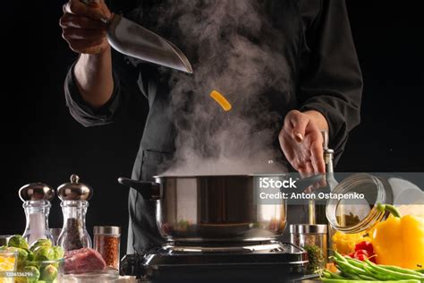 요리 전문가 또는 요리사가 드레싱에서 수프 또는 이탈리아 파스타를 요리합니다 야채의 배경에 대해 증기로 팬을 가열합니다 레시피 책 요리 미식 모션 동결 고급 요리에 대한