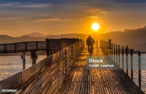 역사적인 Holzsteg 보행자 다리 Crossinhg 위 취리히 호수 세인트 제임스의 오래 된 방법 스위스의 일부에가 춘 분 동안 극적인 일출 동안 자전거 경관에 대한
