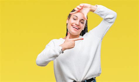 젊은 꼰 머리 아프리카계 미국인 여자 웃는 행복 한 얼굴로 손가락과 손으로 만드는 프레임 격리 된 배경 위에 겨울 스웨터를 입고 창의력과 사진 개념입니다 땋은 머리에 대한