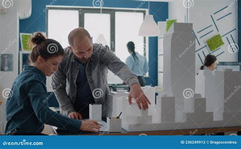 Man And Woman Analyzing Blueprints Plan And Building Model To Design Urban Construction Stock