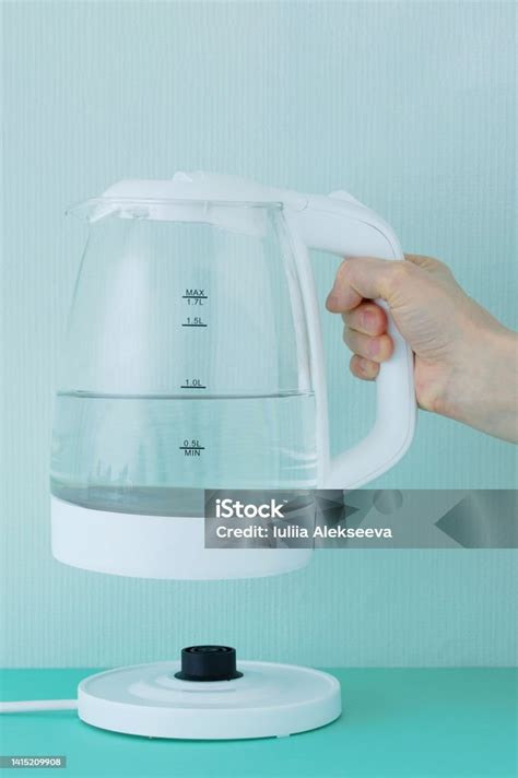 손에 물이 든 흰색 유리 주전자 주전자를 전기 플랫폼에 놓습니다 끓음에 대한 스톡 사진 및 기타 이미지 끓음 물 전기