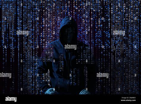Silhouette Of Anonymous Hacker And Digital Binary Code On Dark