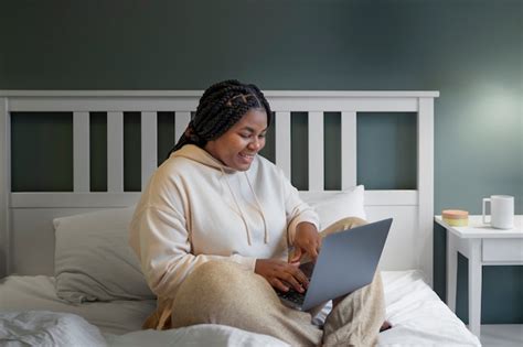 침대 전체 샷에 노트북을 가진 여자 무료 사진