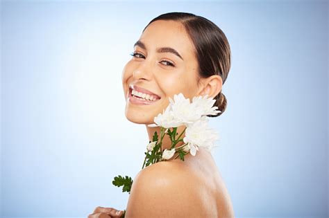 얼굴 초상화 스킨케어 파란색 배경 모형에 스튜디오에 꽃을 든 여자 유기농 메이크업 꽃 화장품 및 얼굴 치료 건강한 피부 및 미용을 위한 흰색 식물을 가진 여성 모델 꽃