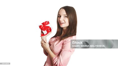 선물 상자를 들고 카메라를보고 드레스에 행복한 이빨 미소 소녀의 초상화 갈색 머리 젊은 여성은 휴일 생일선물을받습니다 흰색 배경 발렌타인 갈색 머리에 대한 스톡 사진 및