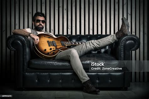 일렉트릭 기타 빈티지 소파에 앉아 함께 성인 백인 기타리스트 초상화 소파와 현대 나무 벽에 음악이 수 개념 남성에 대한 스톡 사진 및 기타 이미지 Istock