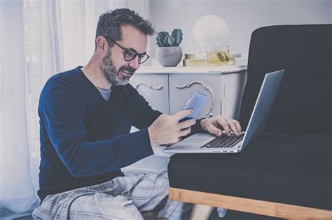 남자는 집에서 지상에 앉아 노트북과 함께 작동합니다 원격 사무실집에서 일하는 남성 소년은 거실에서 온라인 장치를 사용합니다 홈