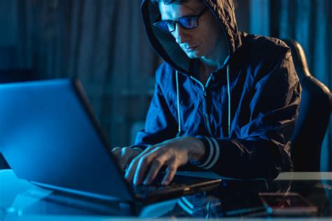 hacker in the hood typing program code while stealing access databases