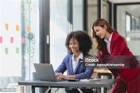 사무실에서 함께 일하고 상담하는 두 명의 행복한 사업가 사무실 책상에서 노트북을 통해 동료와 토론하는 사업가 20 24세에 대한 스톡 사진 및 기타 이미지 Istock