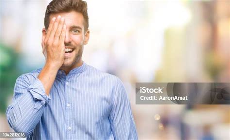 잘생긴 젊은이 얼굴과 놀라운 감정에 확신 미소와 함께 손으로 한쪽 눈을 덮고 격리 된 배경 위에 가리기에 대한 스톡 사진 및 기타 이미지 Istock
