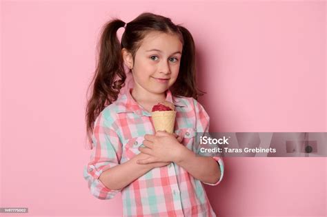 사랑스러운 소녀는 초콜릿 딸기 아이스크림과 함께 와플 콘을 들고 카메라를 바라보며 미소를 짓고 분홍색으로 고립되어 있다 6 7