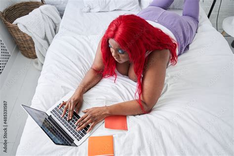 Foto De Female Laying On The Bed With Notebook And Typing At The Laptop Keyboard While Studying