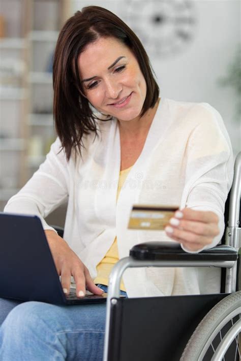 Senior Woman In Wheelchair Typing Card Number On Laptop Stock Image