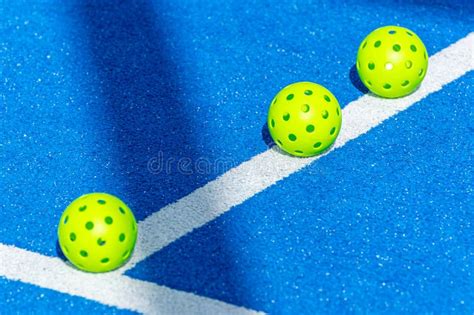Three Balls Of Pickleball On The Line Ina Blue Court Racket Sport Concept Background Stock