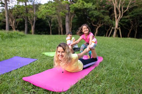 어린 딸이 공공 공원에서 요가 매트에 활 포즈를 취하는 어머니를 돕습니다 12 13세에 대한 스톡 사진 및 기타 이미지 12 13세 야외 요가 Istock