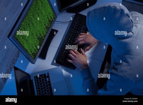 High Angle View Of Hacker In Hooded Jacket Using Computer At Table