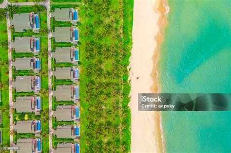 공중 평면도 바다 해안 해변 바다에 빽빽하게 지어진 정원이있는 많은 동일한 라인 행 건물 집들은 코코넛 야자수와 하얀 모래가 수정처럼 맑은 푸른 물에 묻혀 있습니다 0명에