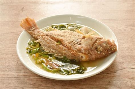 Spicy Boiled Fried Red Bass Fish And Herb In Tom Yum Soup On Plate