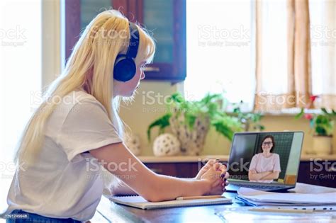 헤드폰을 착용한 십대 여학생이 노트북을 사용하여 집에 앉아 교사와 대화하는 경우 18 19세에 대한 스톡 사진 및 기타 이미지 18 19세 2명 가정 생활 Istock