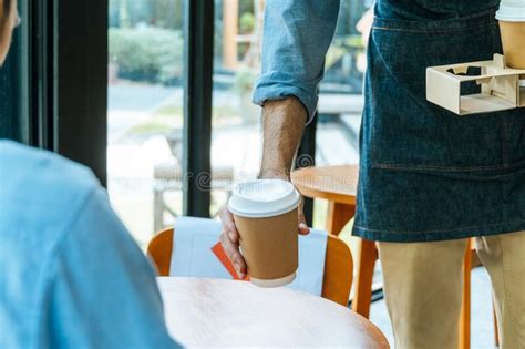 Asian Staff Wearing Apron Serving Hot Black Coffee Cup To Customer On Table In Cafe Coffee Shop
