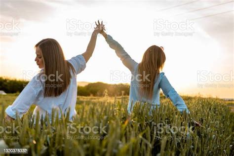 밀밭에 서 있는 두 명의 청녀 그들은 밀밭 한가운데 서 팔을 들고 손을 들고 서 있었다 2명에 대한 스톡 사진 및 기타 이미지