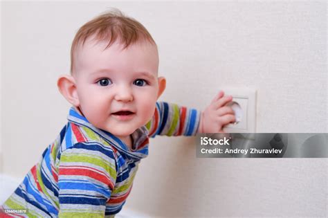 아기 유아는 손으로 집 벽에 있는 전기 콘센트에 손을 뻗습니다 감전으로부터 어린이 손가락의 위험과 보호 콘센트에 대한 스톡 사진 및 기타 이미지 Istock