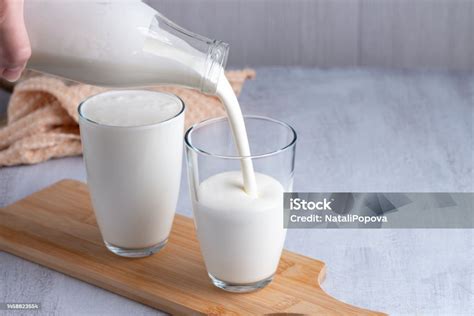 수제 케 피어 버터 밀크 또는 요구르트를 프로바이오틱스와 함께 붓습니다 밝은 배경에 유리 병에서 흐르는 요구르트 프로바이오틱 차가운 발효 유제품 음료 트렌디 한 음식과 음료