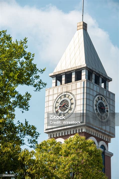 Clock Tower With Dual Clocks Surrounded By Trees Under A Clear Blue Sky