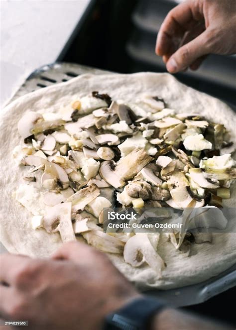 손으로 쭉 뻗은 반죽에 신선한 버섯과 치즈를 곁들인 생 펑기 피자를 준비하는 셰프의 클로즈업 전문 피자 가게 주방에서 전통 이탈리아 피자 만들기 과정 가정 주방에 대한 스톡