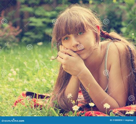 Красивая маленькая девочка лежа на зеленой траве внешней Стоковое Фото изображение