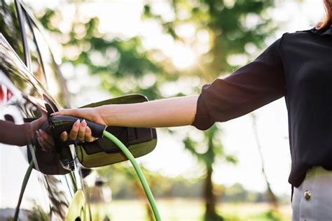 Premium Photo Female Hand Plugging In A Charger In Opened Charging Socket On A Black Electric