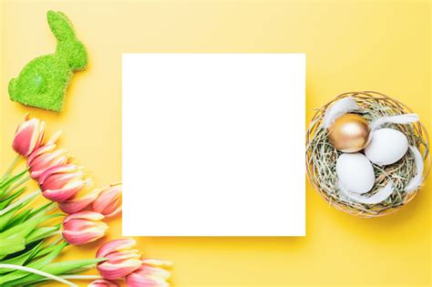 부활절 달걀 바구니 봄 튤립바구니에 황금 달걀 해피 부활절 장식에서 파스텔 노란색 배경에 흰색 깃털 태양 빛에 전통적인 장식 맨 위 보기입니다 4월에 대한 스톡 사진 및