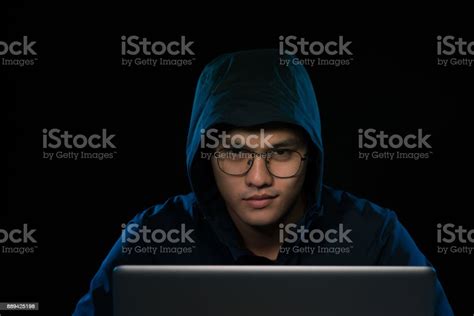 Asian Hacker Hacking Computer Network With Laptop In Dark Cyber