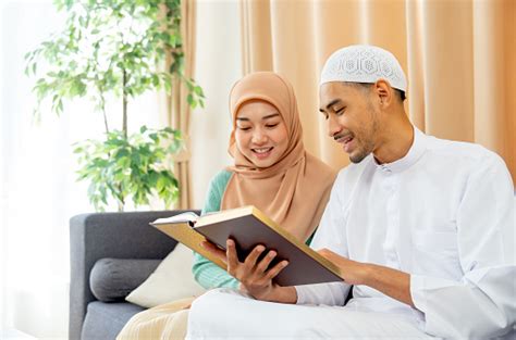무슬림 남성과 여성 커플이 소파에 앉아 함께 이슬람 교육 서적을 읽고 행복한 미소를 짓는 모습 25 29세에 대한 스톡 사진 및 기타 이미지 Istock