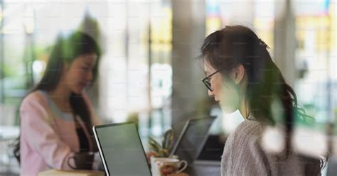 유리창을 통해 카페에서 노트북으로 작업하는 두 여성의 모습 사진 Unsplash의 기술 이미지