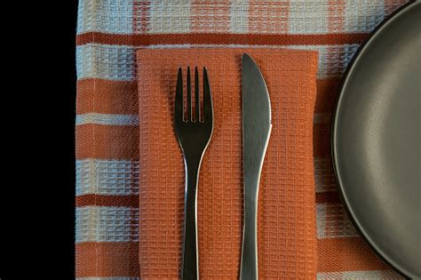 금속 포크 오렌지 냅킨에 칼과 검은 배경에 접시 복사 공간이있는 스테인레스 나이프와 포크의 상단보기 개념에 대한 스톡 사진 및 기타 이미지 Istock