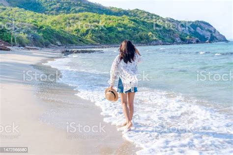 아시아 여성은 주말 여름 휴가 개념 동안 해변에서 밀짚 모자를 들고 바다 파도 산 모래 해변 녹색 바다 걷기에 대한 스톡 사진 및 기타 이미지 Istock
