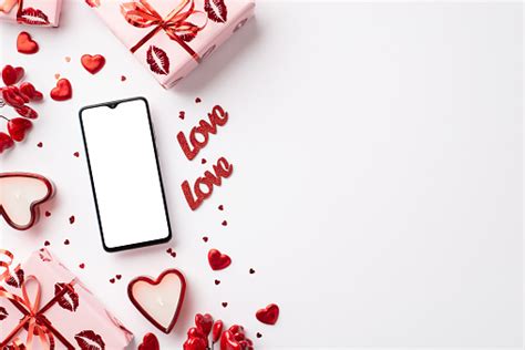 발렌타인 데이 개념입니다 키스 입술 패턴 빨간 마음 색종이 비문 사랑 촛불이 있는 포장지에 스마트 폰 선물 상자의 상위 뷰 사진