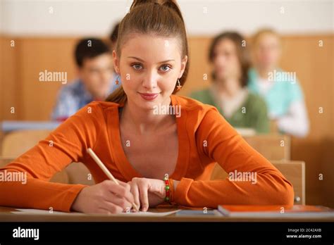 Brunette Girl With Asterisk Earrings Sits At A School Desk Classroom