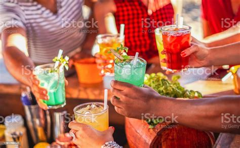 모히토와 재미를 응원 하는 행복 한 사람들 코로나 바이러스로부터 보호 할 수있는 얼굴 마스크와 함께 여름철 바 밖의 해변 바에서 코크 테일을 마시는 다민족 친구 특별 할인