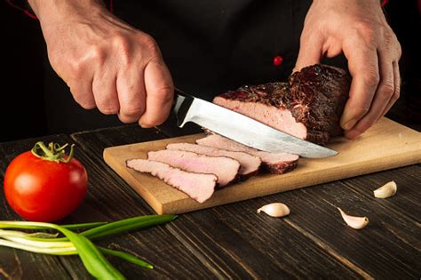 요리사가 텍스트 메뉴 또는 레시피를 위한 복사 공간이 있는 어두운 검은색 배경에 육즙이 많은 쇠고기 스테이크를 요리합니다 검은