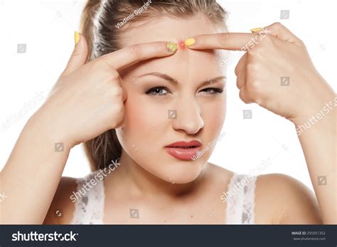 Young Blonde Squeezes A Pimple On Her Forehead Stockfoto 295951352