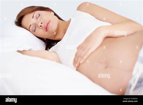 Catching some sleep for important development. Young pregnant woman sleeping on her bed with her ...