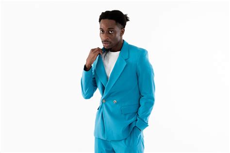 잘 생긴 아프리카 계 미국인 Buisnessman은 스튜디오에서 흰색 배경에 서서 스마트 블루 슈트와 주머니에 손을 잡고있는 흰색 티셔츠를 입은 카메라를 보면서